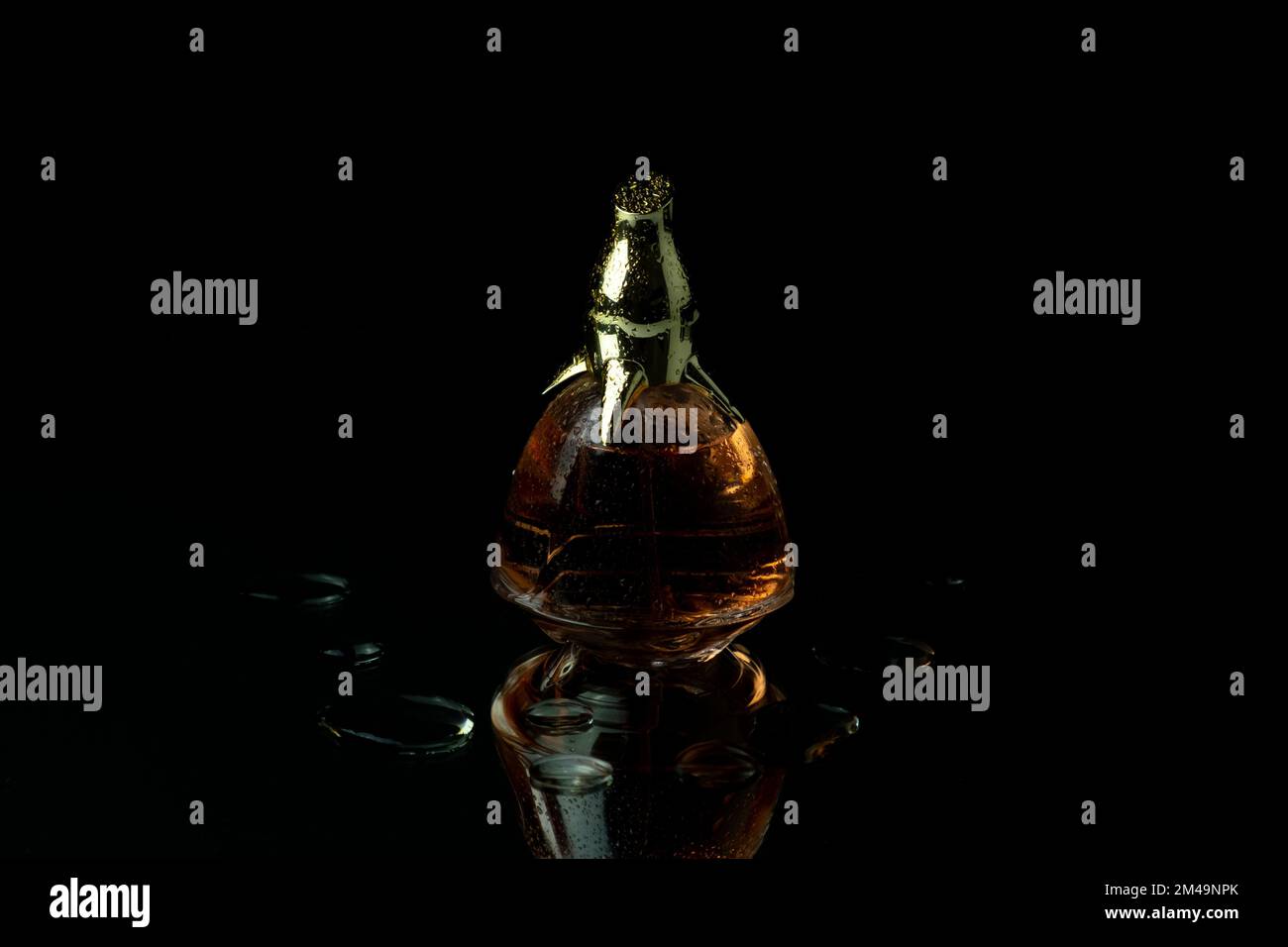A bottle of a women's perfume covered in water drops against a black ...