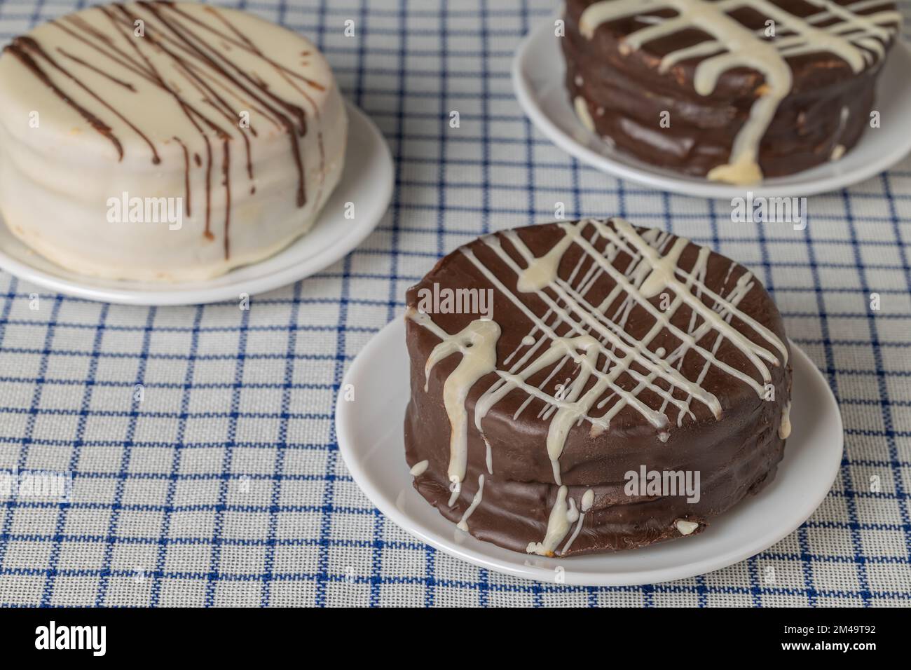 Three alfajores, typical candy in Argentina, on a checkered tablecloth ...