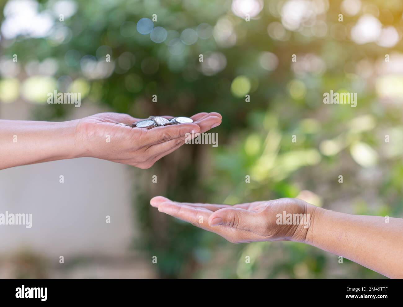 Woman hand give money coin to hand on out of focus background Stock ...
