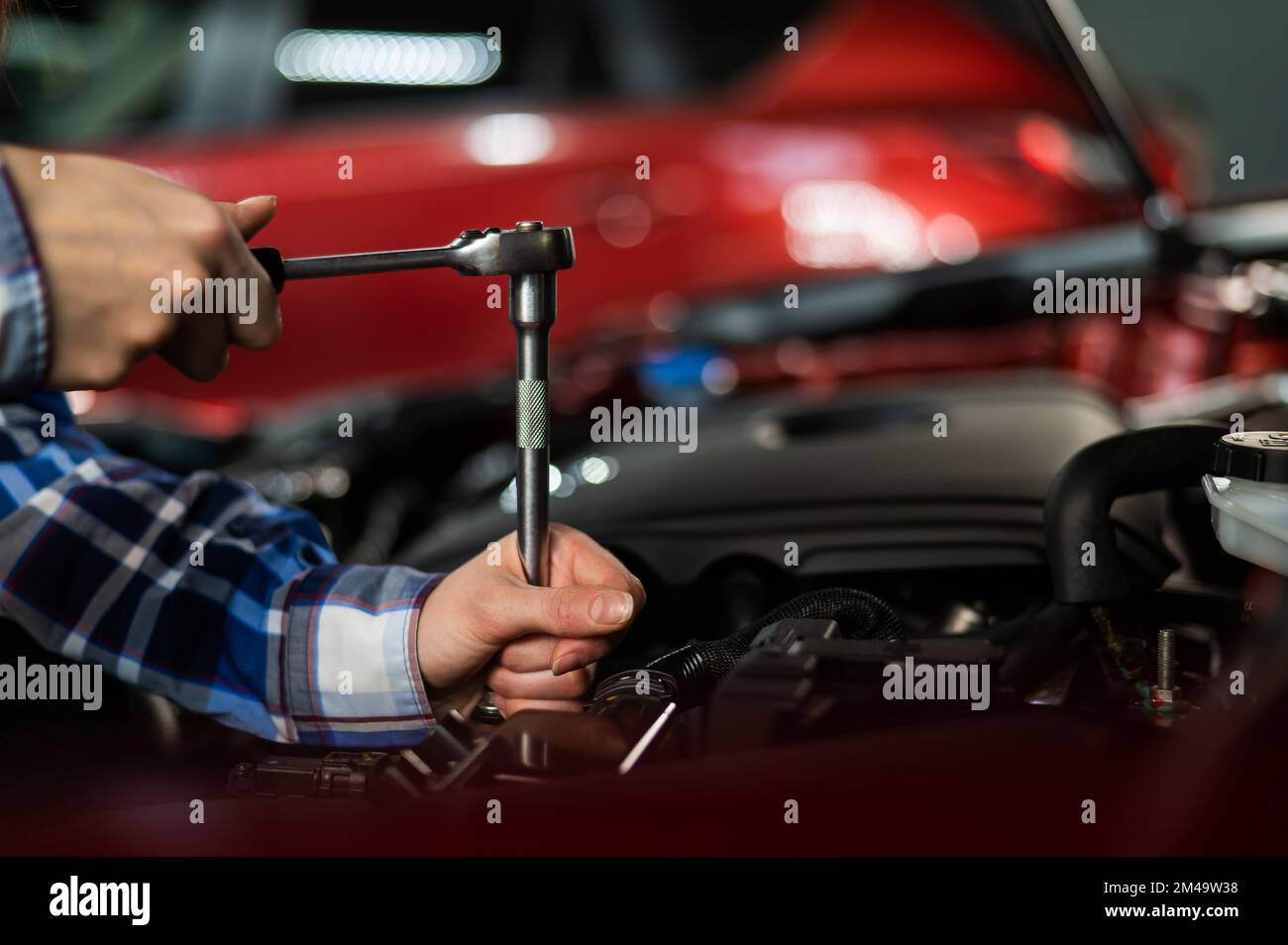 Female auto mechanic unscrewing a nut to replace a car spark plug Stock ...
