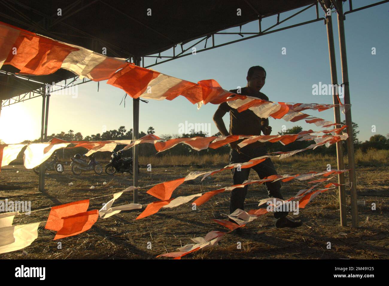 A man placing lines of small decorative flags coloured in red and white ...