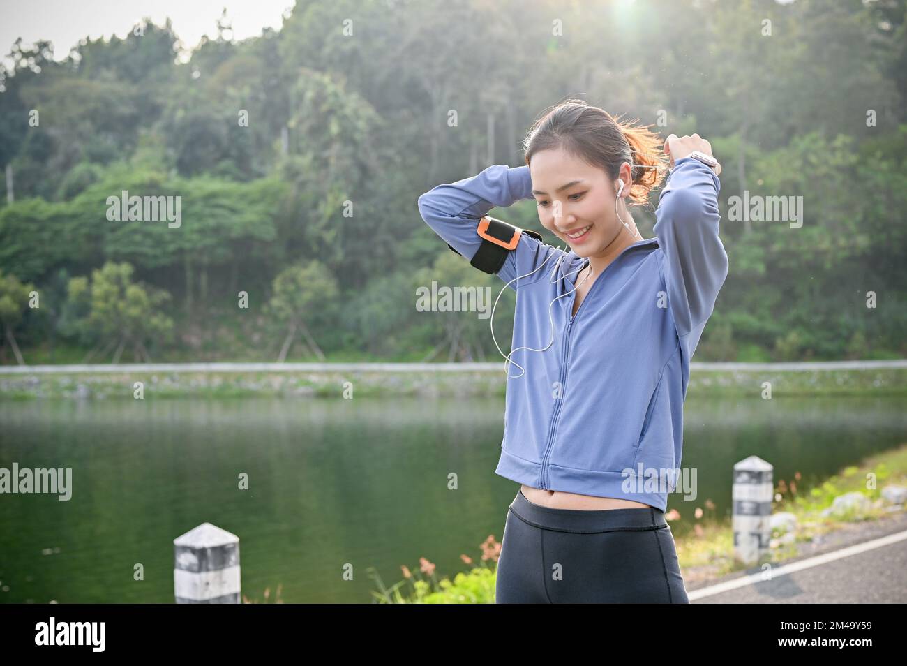 Beautiful and attractive young Asian woman in active sportswear ties ...