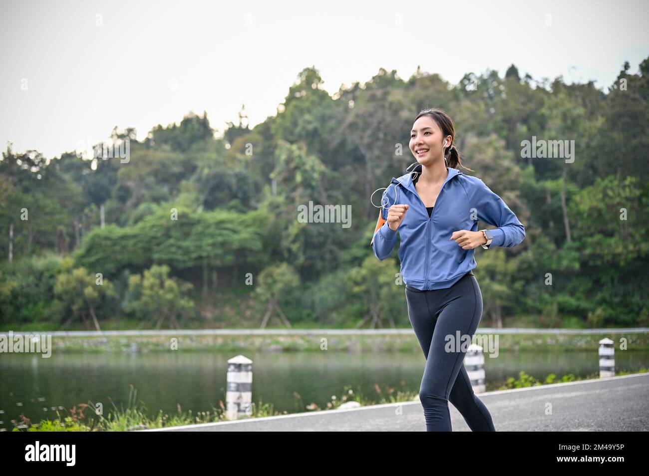 Happy millennial Asian woman in active sportswear listening to music ...