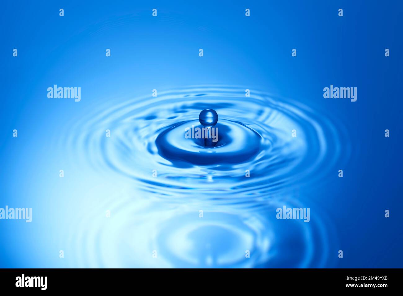 Drops of water falling into deep blue water Stock Photo - Alamy