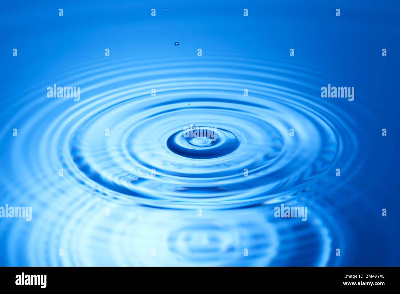 Drops of water falling into deep blue water Stock Photo - Alamy