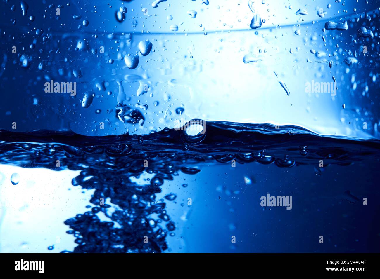 Drops of water falling into deep blue water Stock Photo - Alamy