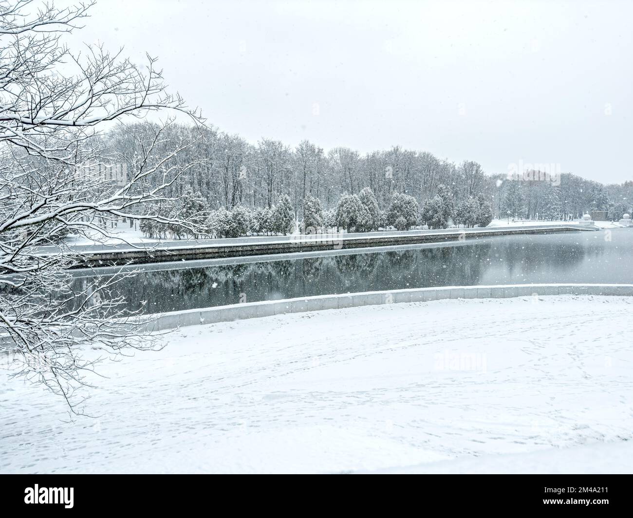 winter scenery with urban embankment and snowy park trees during heavy ...