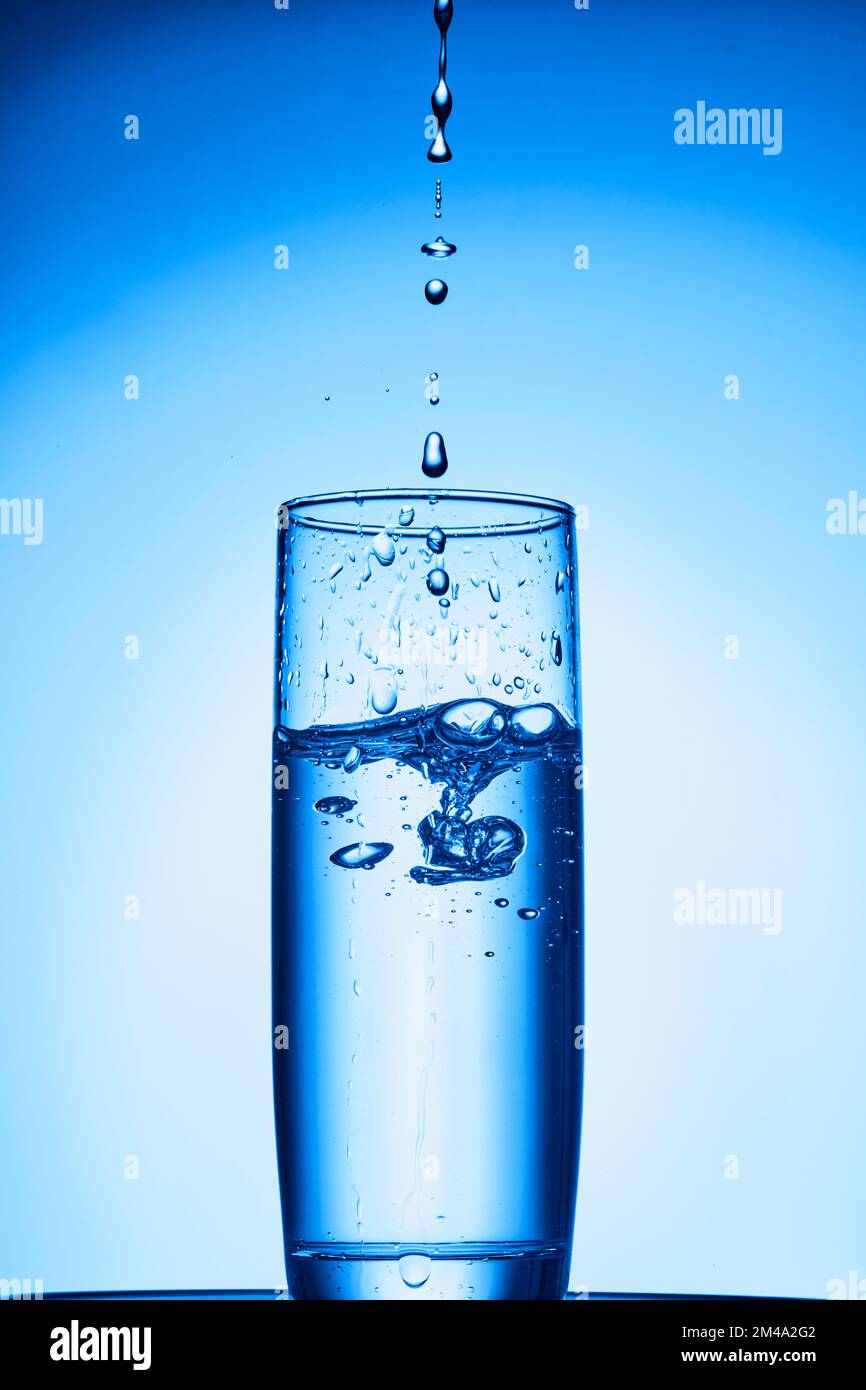Drops of water falling into deep blue water Stock Photo - Alamy