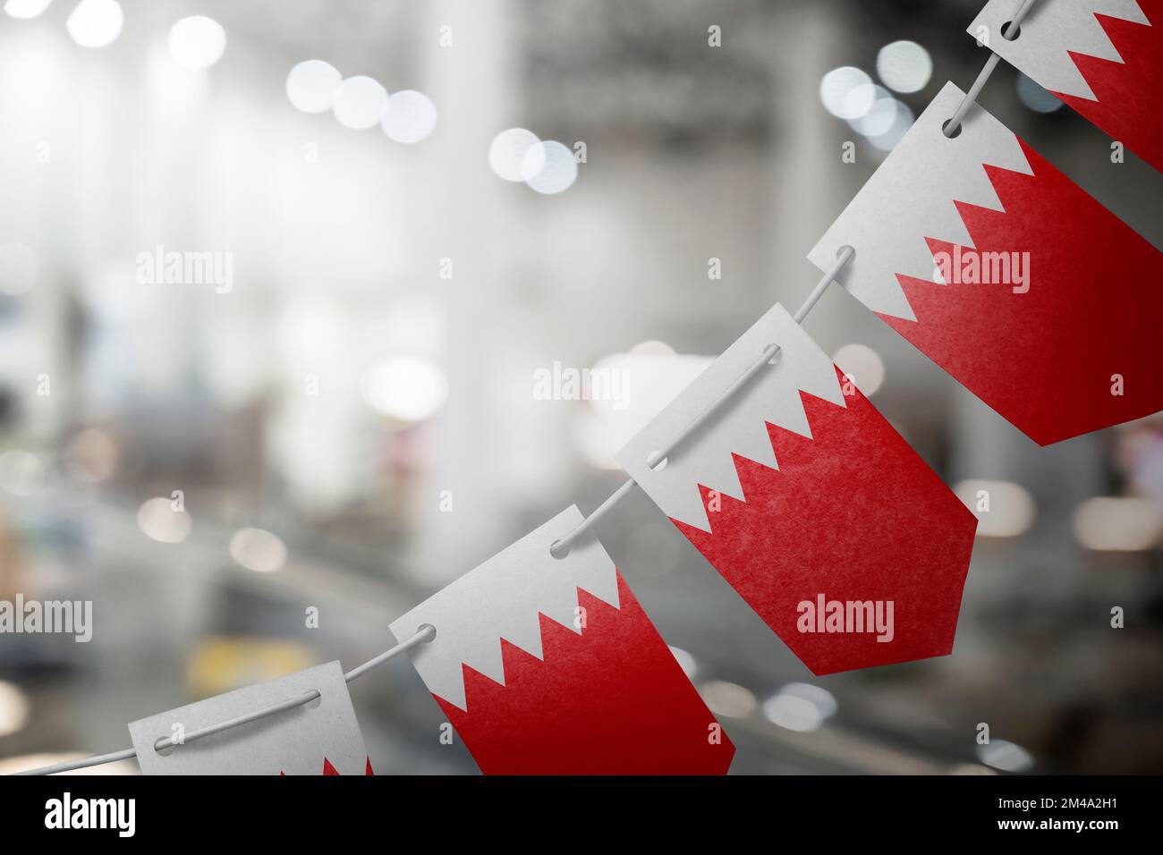 A garland of Bahrain national flags on an abstract blurred background ...