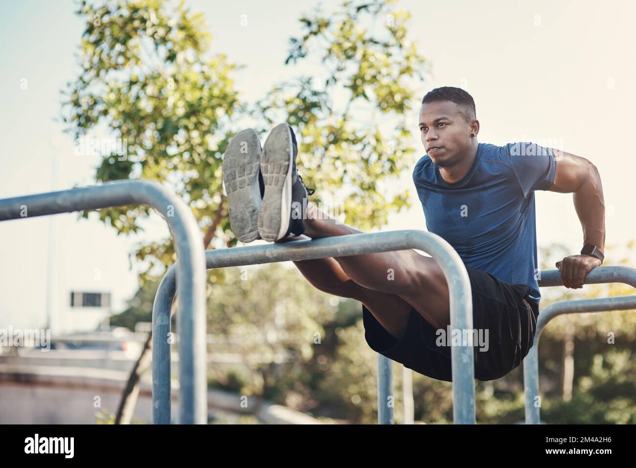 Working the triceps. Full length shot of a handsome young man doing dips while exercising ...