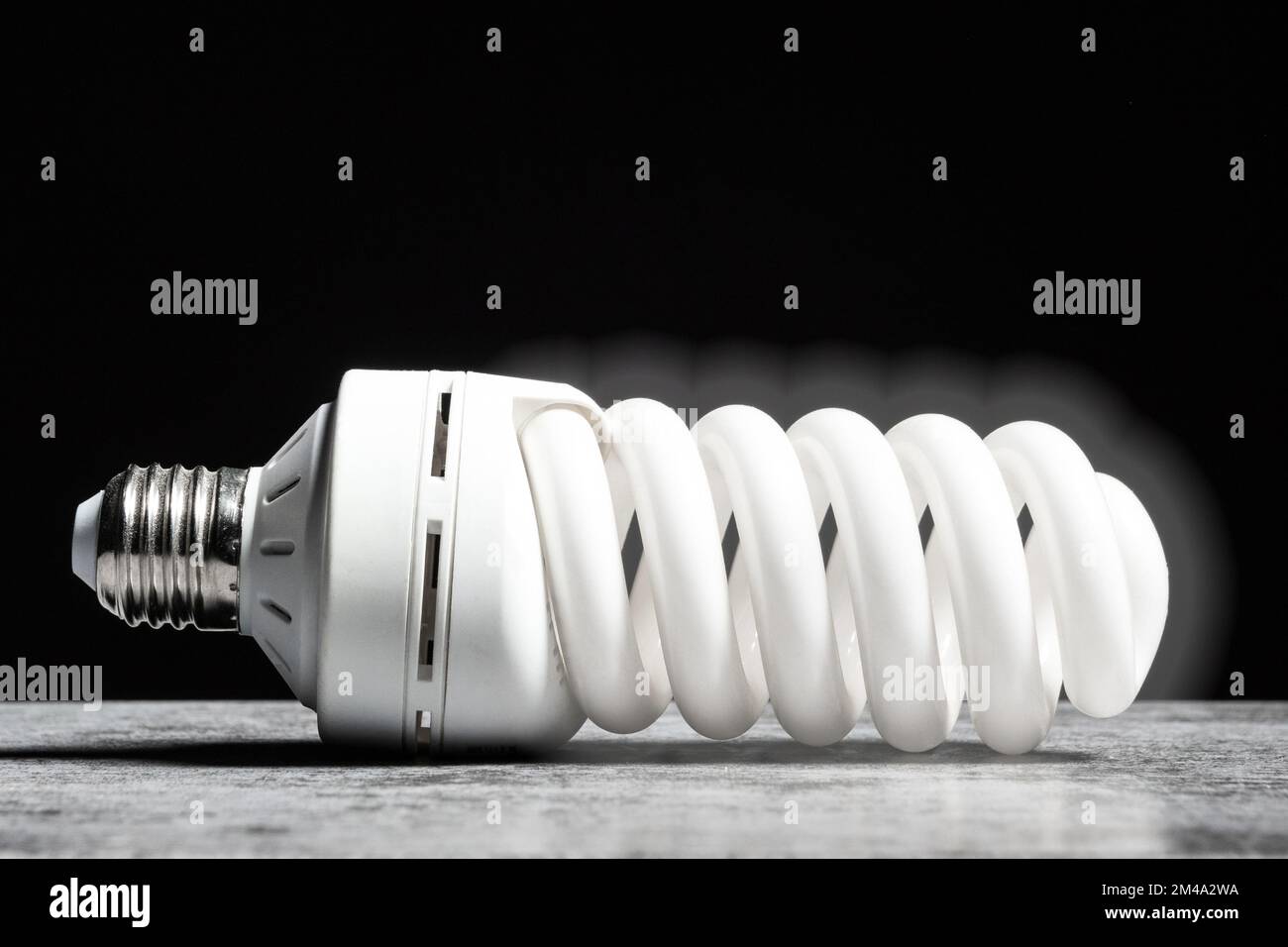 Glowing fluorescent bulb light on the grey table on black background ...