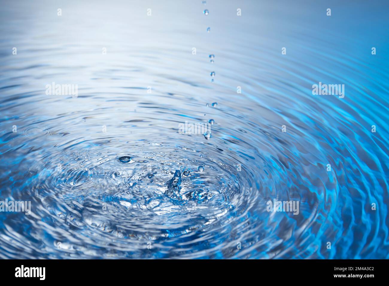 Drops of water falling into deep blue water Stock Photo - Alamy