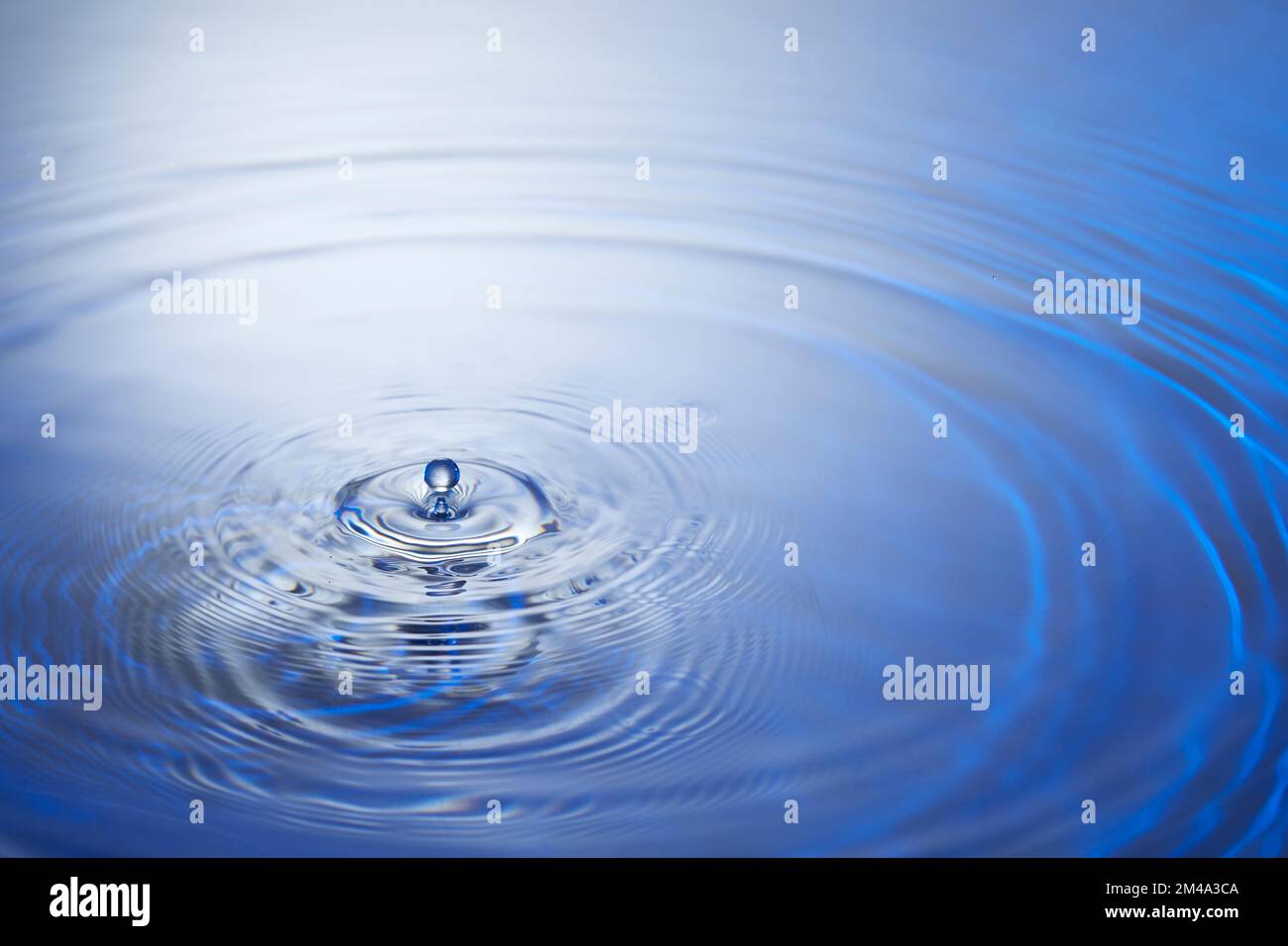 Drops of water falling into deep blue water Stock Photo - Alamy