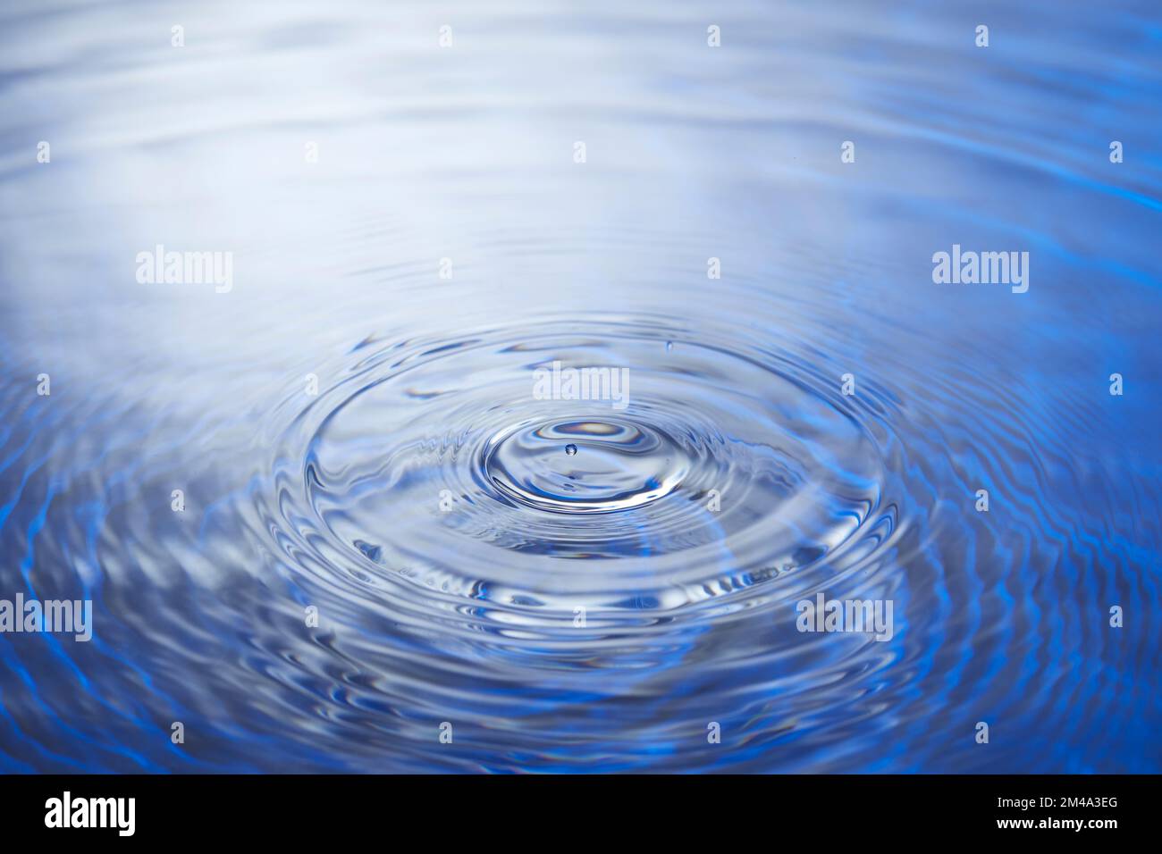 Drops of water falling into deep blue water Stock Photo - Alamy