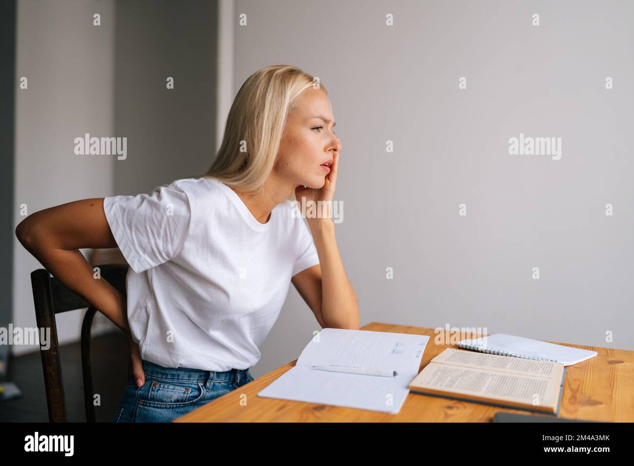 Side view of female student sit at desk touch back suffer from lower ...