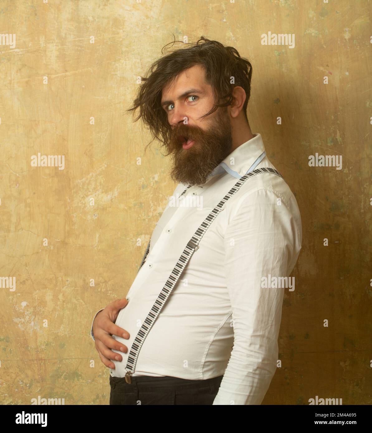 Funny bearded man with uncombed disheveled hair holding her stomach ...