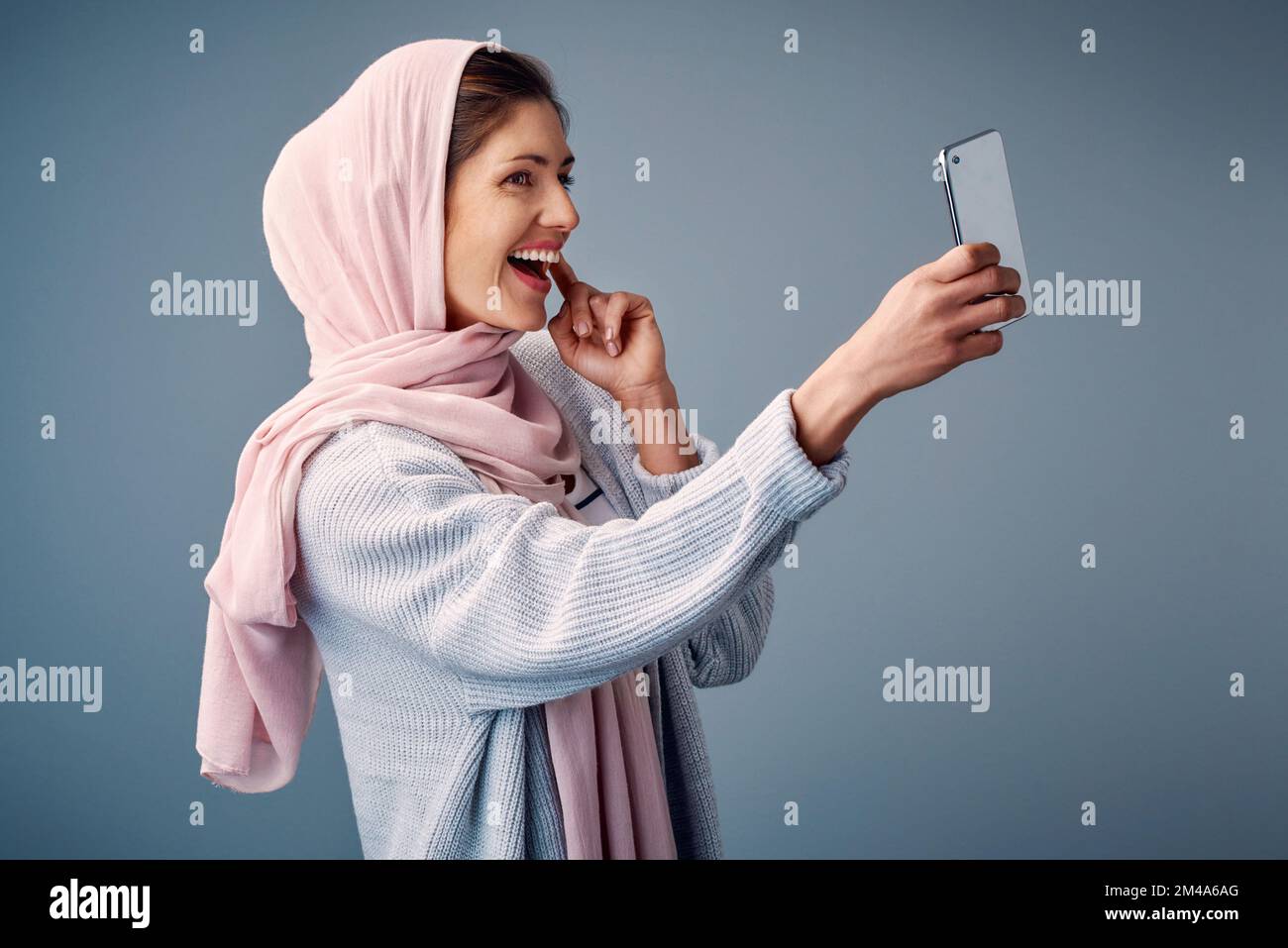 Selfies and smiles. Studio shot of an attractive young woman taking ...