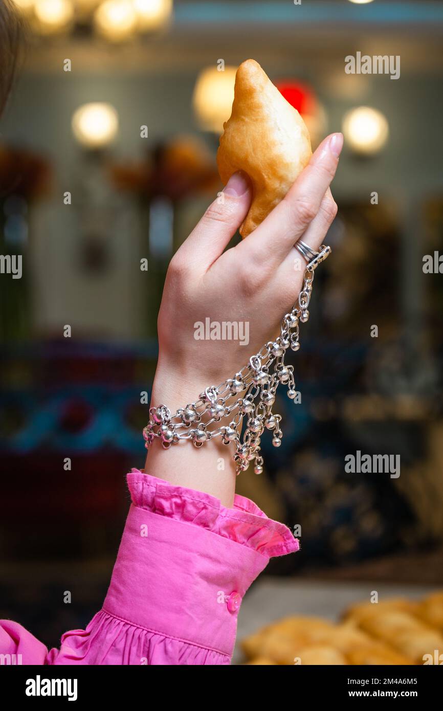 A woman's hand in a national Kazakh decoration holds a baursak on ...