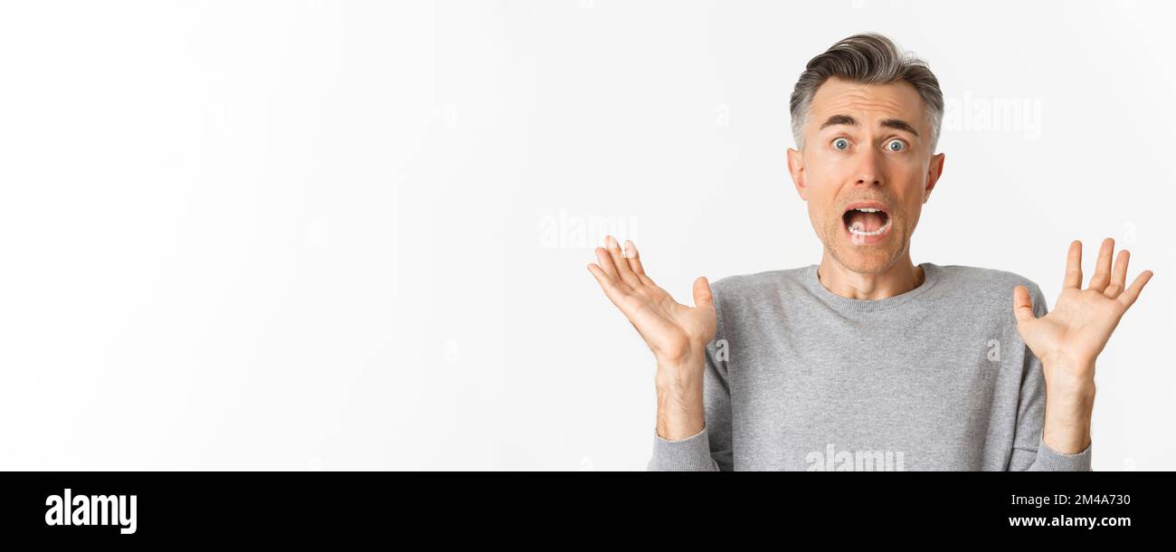 Close-up of scared middle-aged man, looking startled, jumping and screaming frightened, standing ...