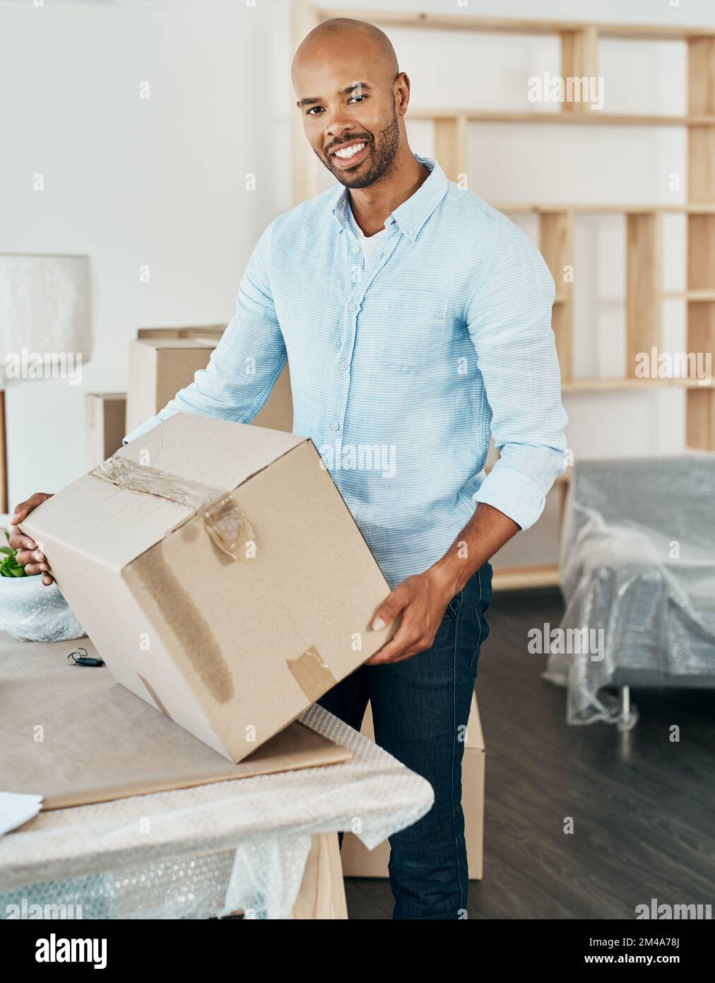 Moving in to his first home. Portrait of a young man carrying a box ...