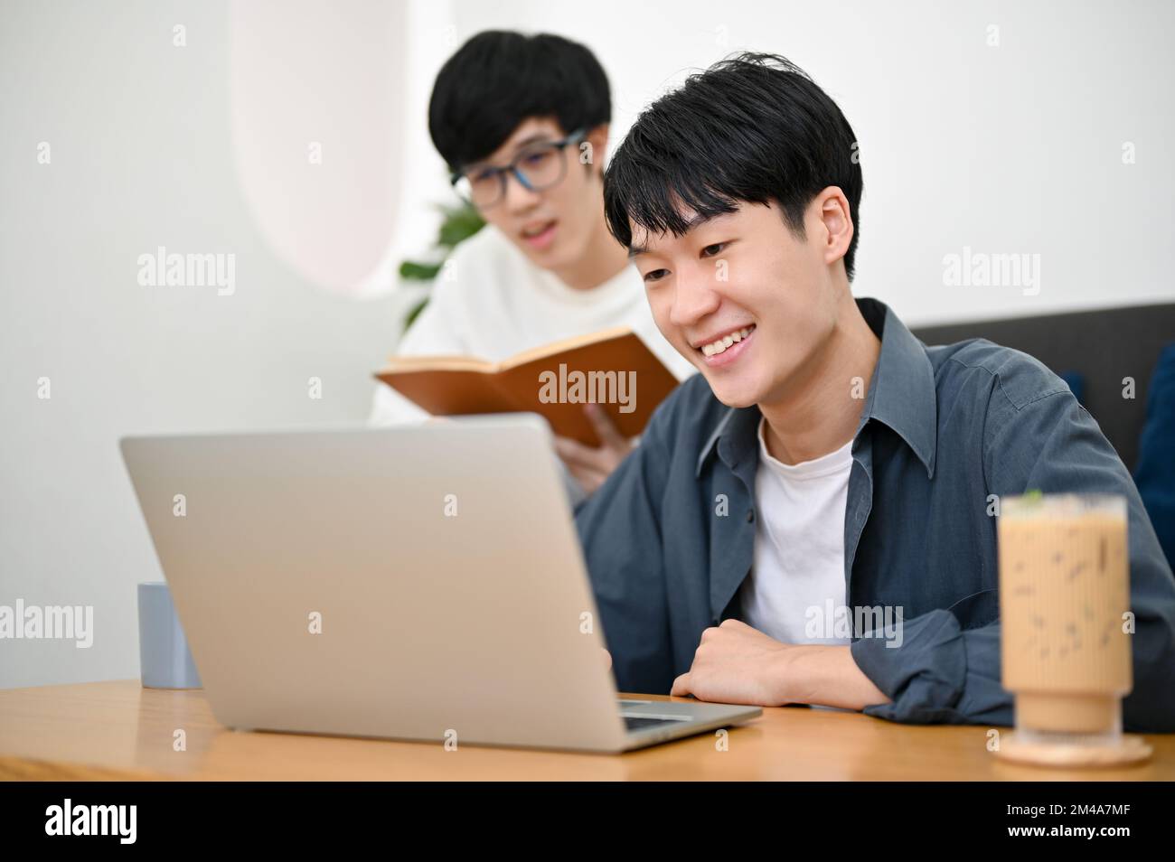 Two of smart young Asian male college students looking at laptop screen ...