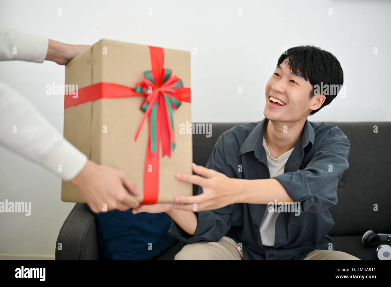 Happy and excited young Asian man receiving a surprise gift box from ...