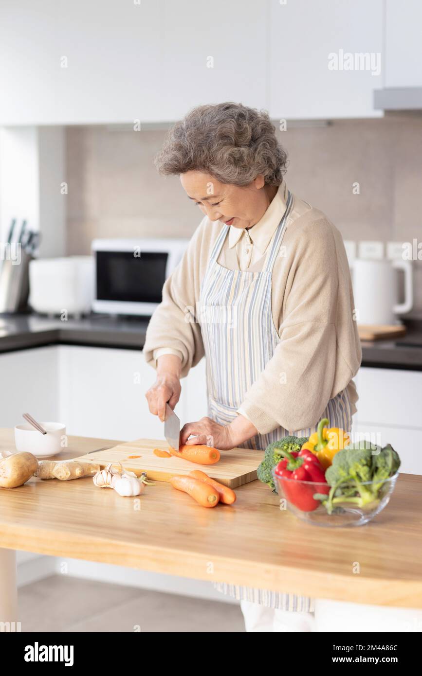 Cheerful senior Chinese woman cooking in kitchen Stock Photo - Alamy
