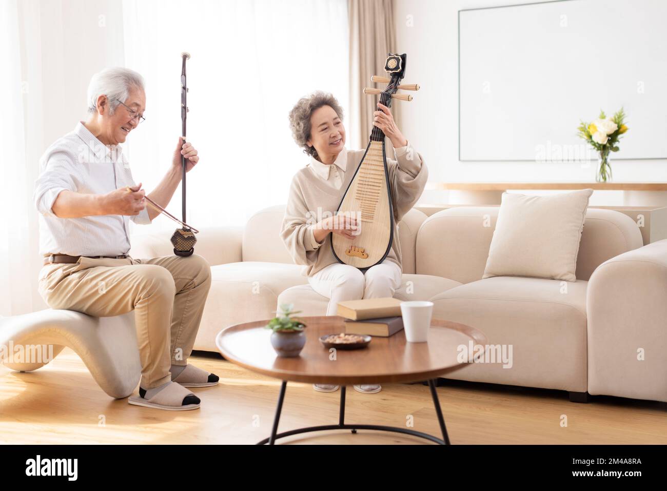 Cheerful senior Chinese couple playing traditional musical instruments ...
