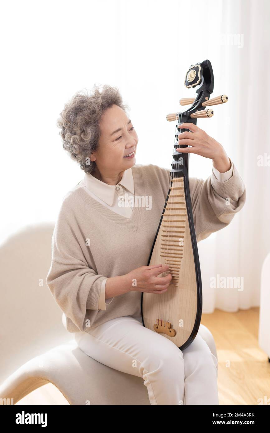 Senior Chinese woman plucking lute Stock Photo - Alamy