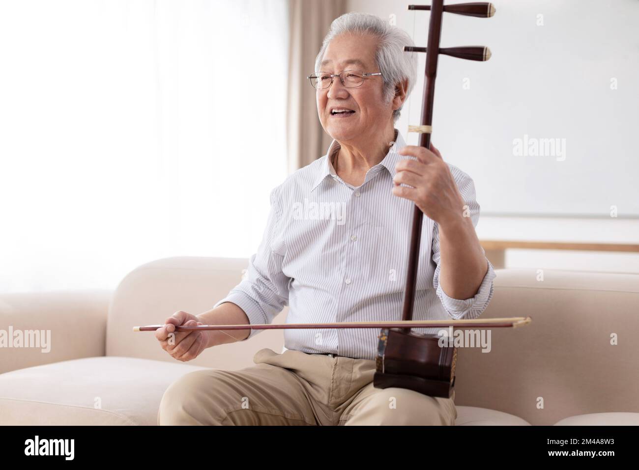 Senior Chinese man playing traditional musical instrument Erhu Stock ...