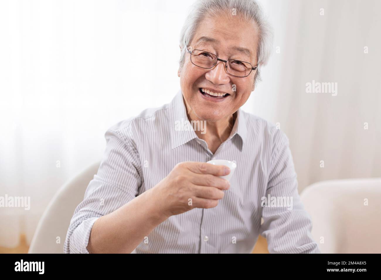 Cheerful senior Chinese man drinking tea Stock Photo - Alamy