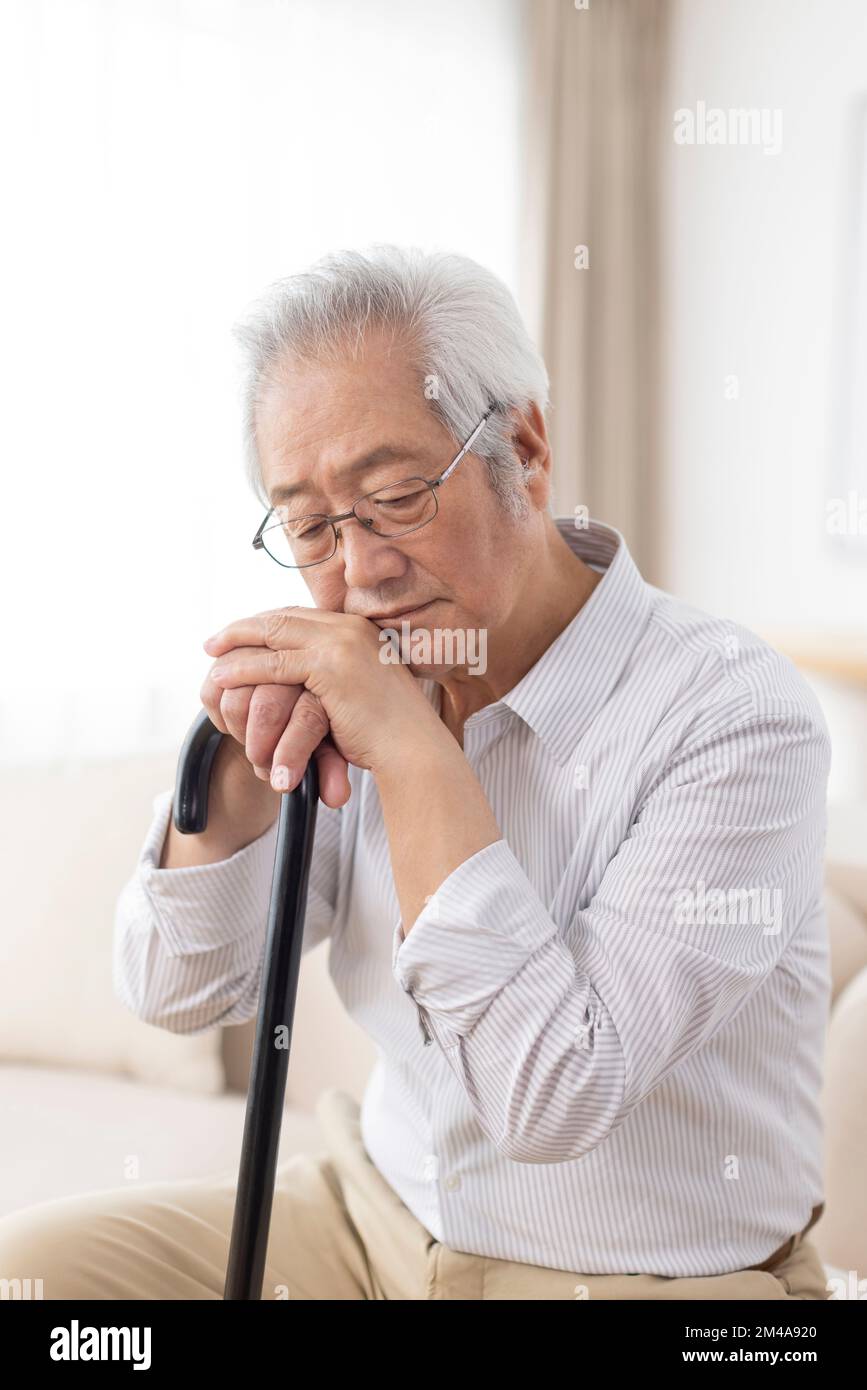 Lonely senior Chinese man sitting on sofa Stock Photo - Alamy