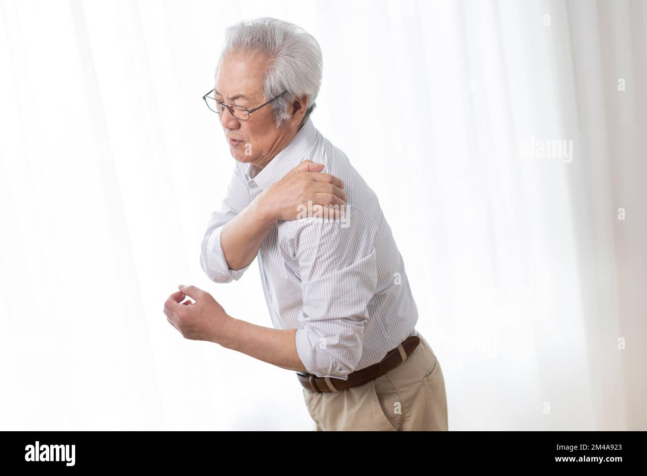 Senior Chinese man suffering from pain on shoulder Stock Photo - Alamy