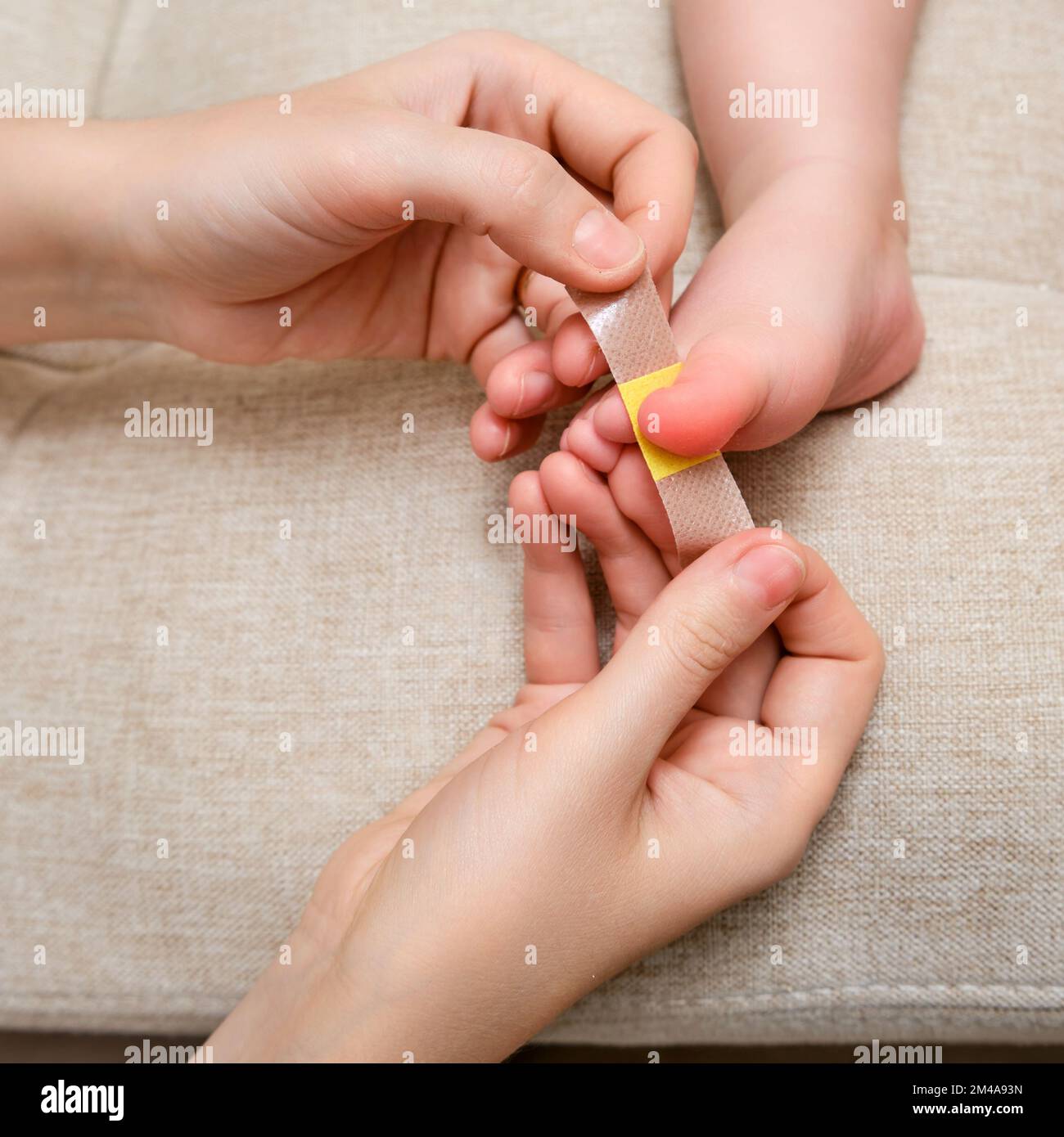 Mother woman sticks a medical adhesive plaster on the toddler baby leg ...