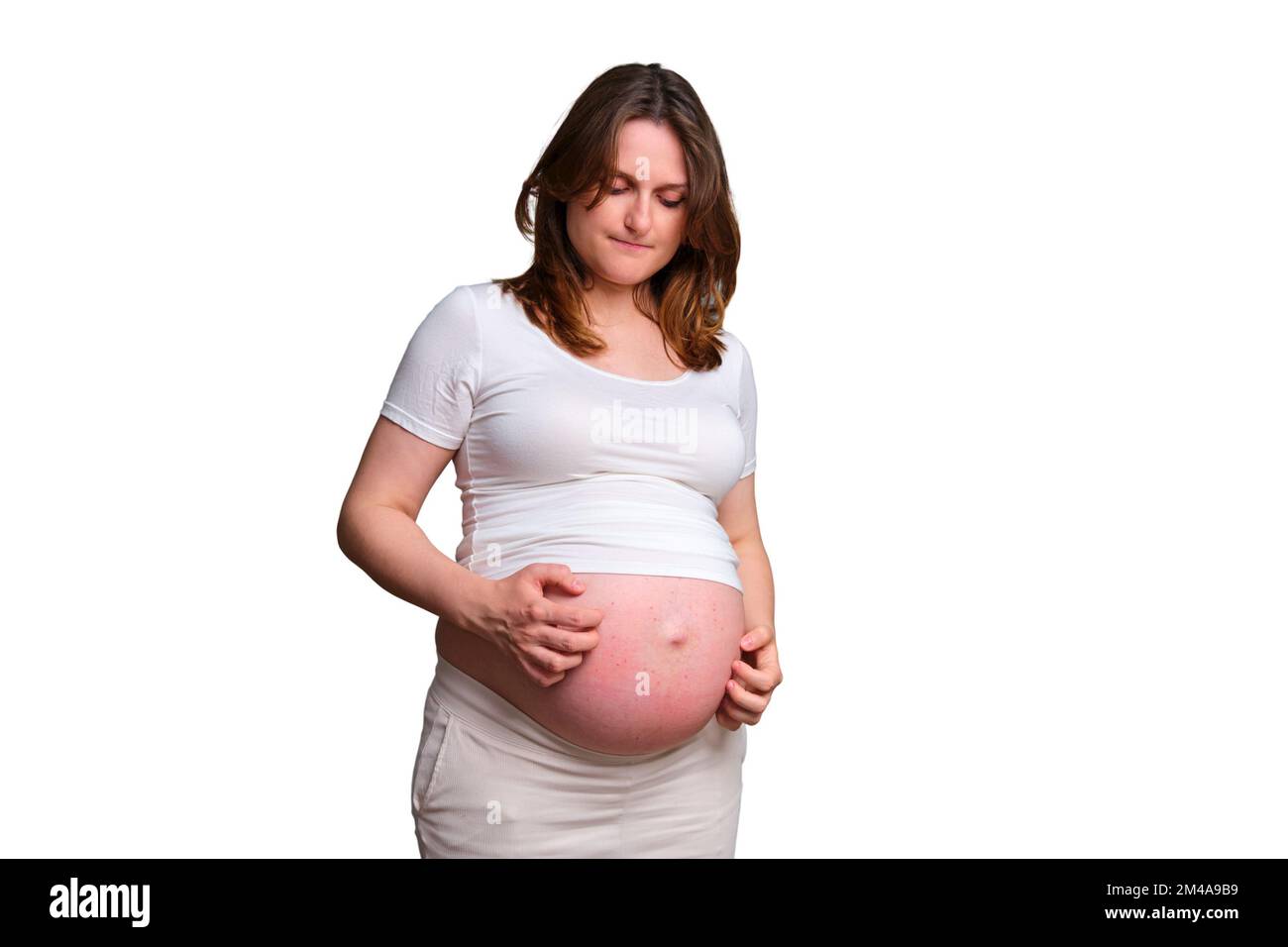 Portrait of a pregnant woman scratching her stomach, white background ...