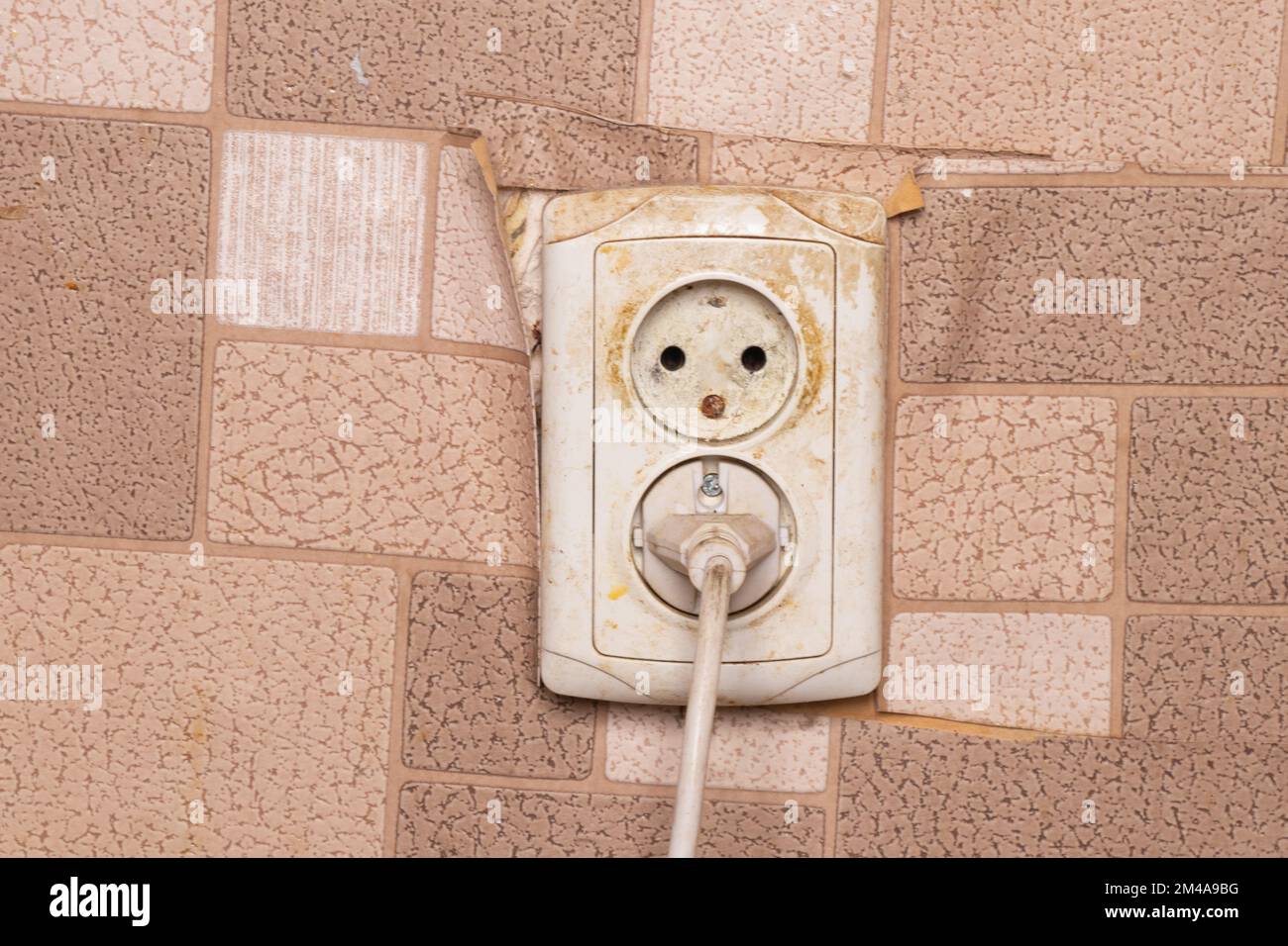 dirty outlet with a plug on the wall of a house Stock Photo - Alamy