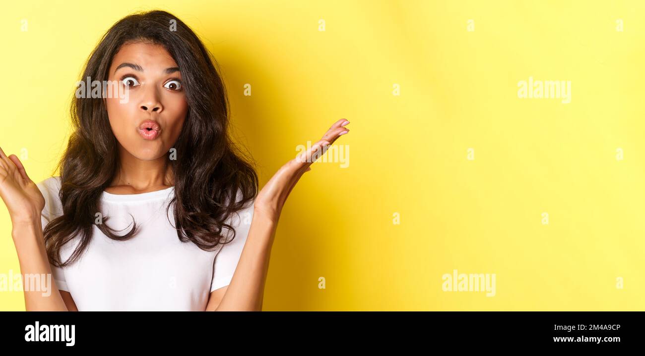 Close-up of surprised african-american girl, raising hands up and ...