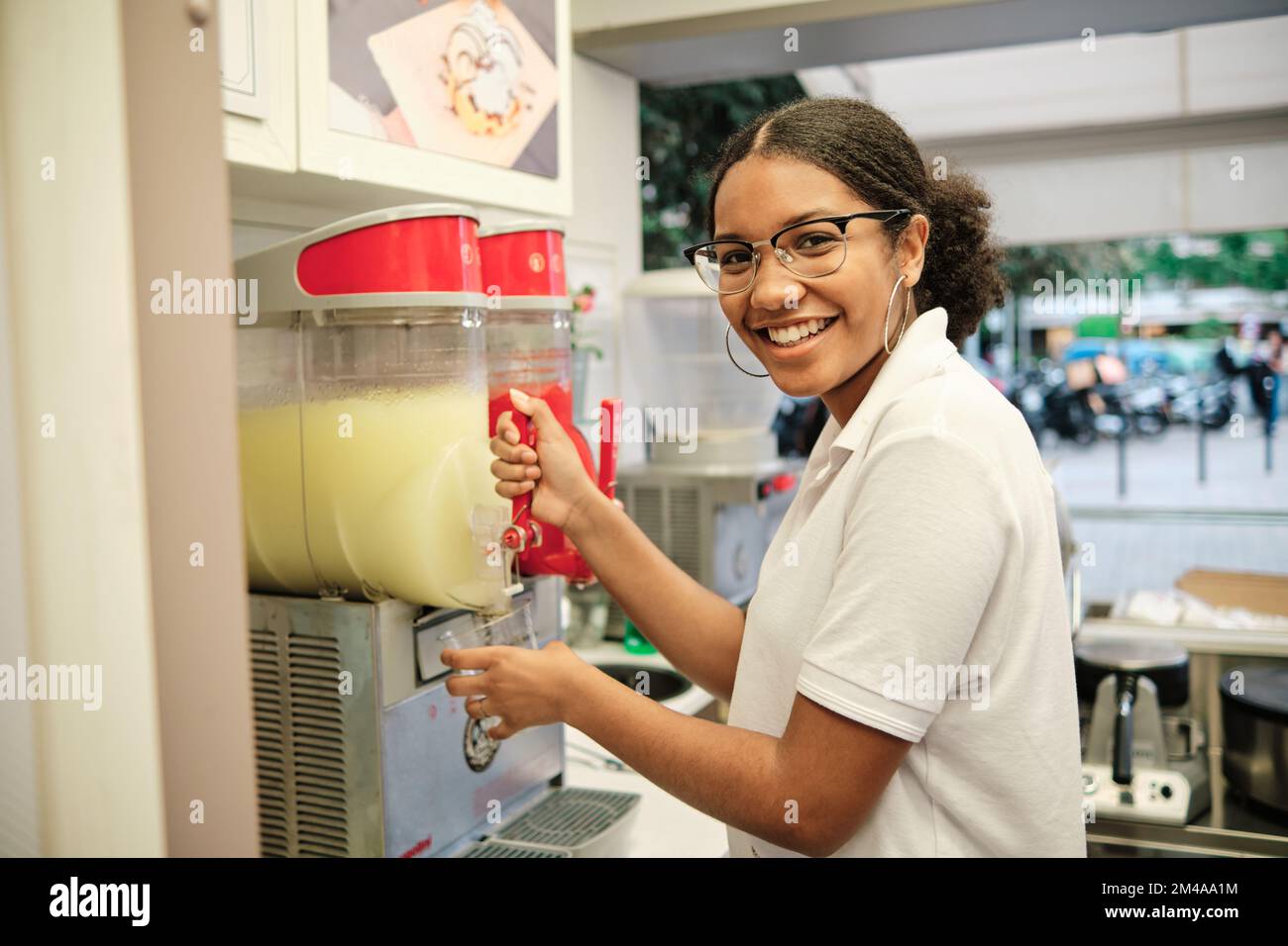 Smiling worker serving a lemon from a drinkk dispenser Stock Photo - Alamy