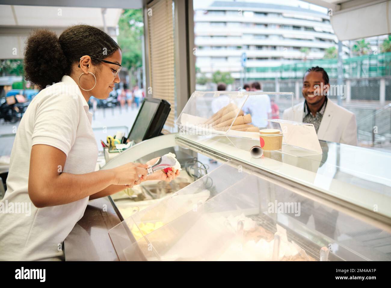 Worker attending a client in an ice cream shop Stock Photo - Alamy
