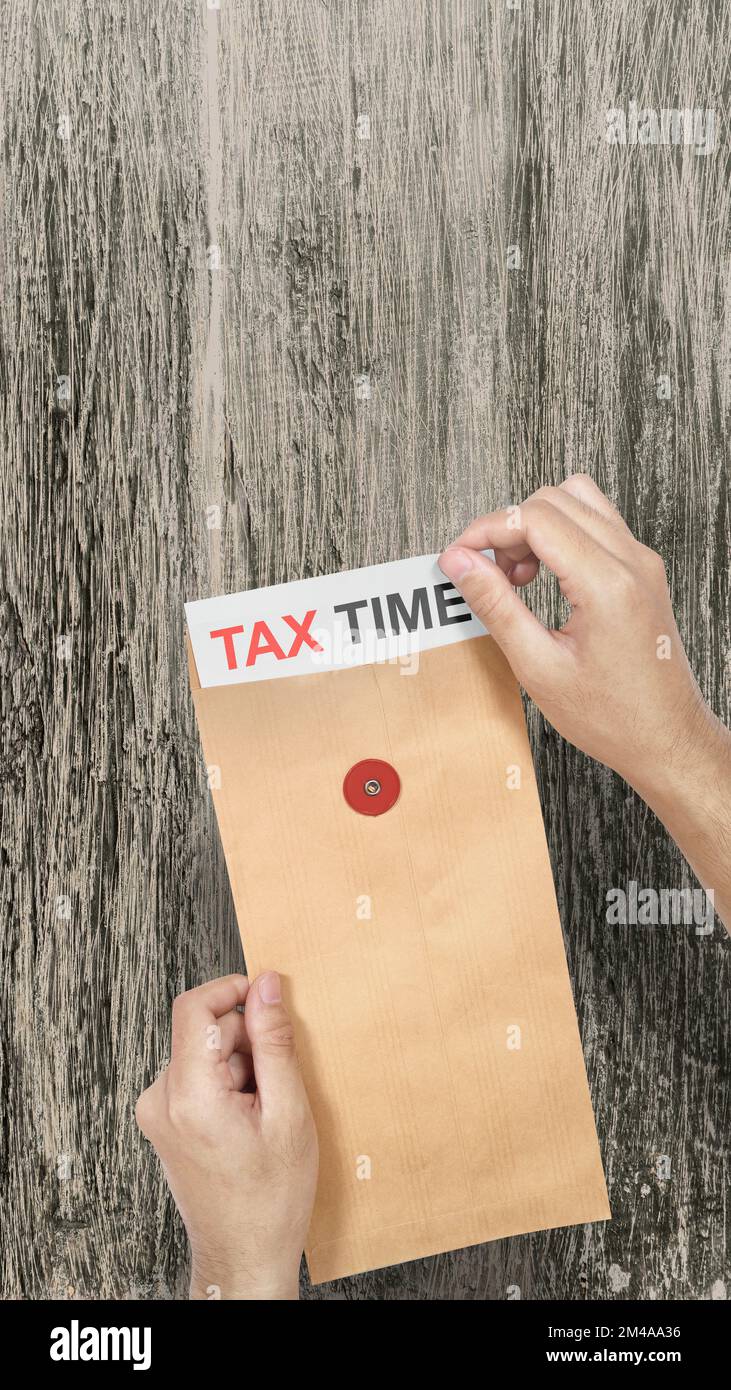 Human hand opening envelope with tax time notes on wooden background ...
