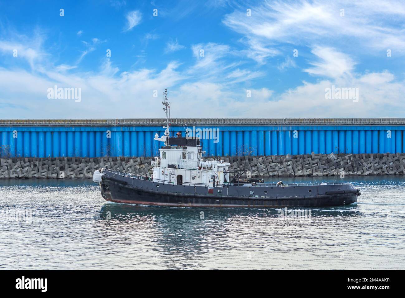 The tugboat passes in the strait of the city port Stock Photo - Alamy