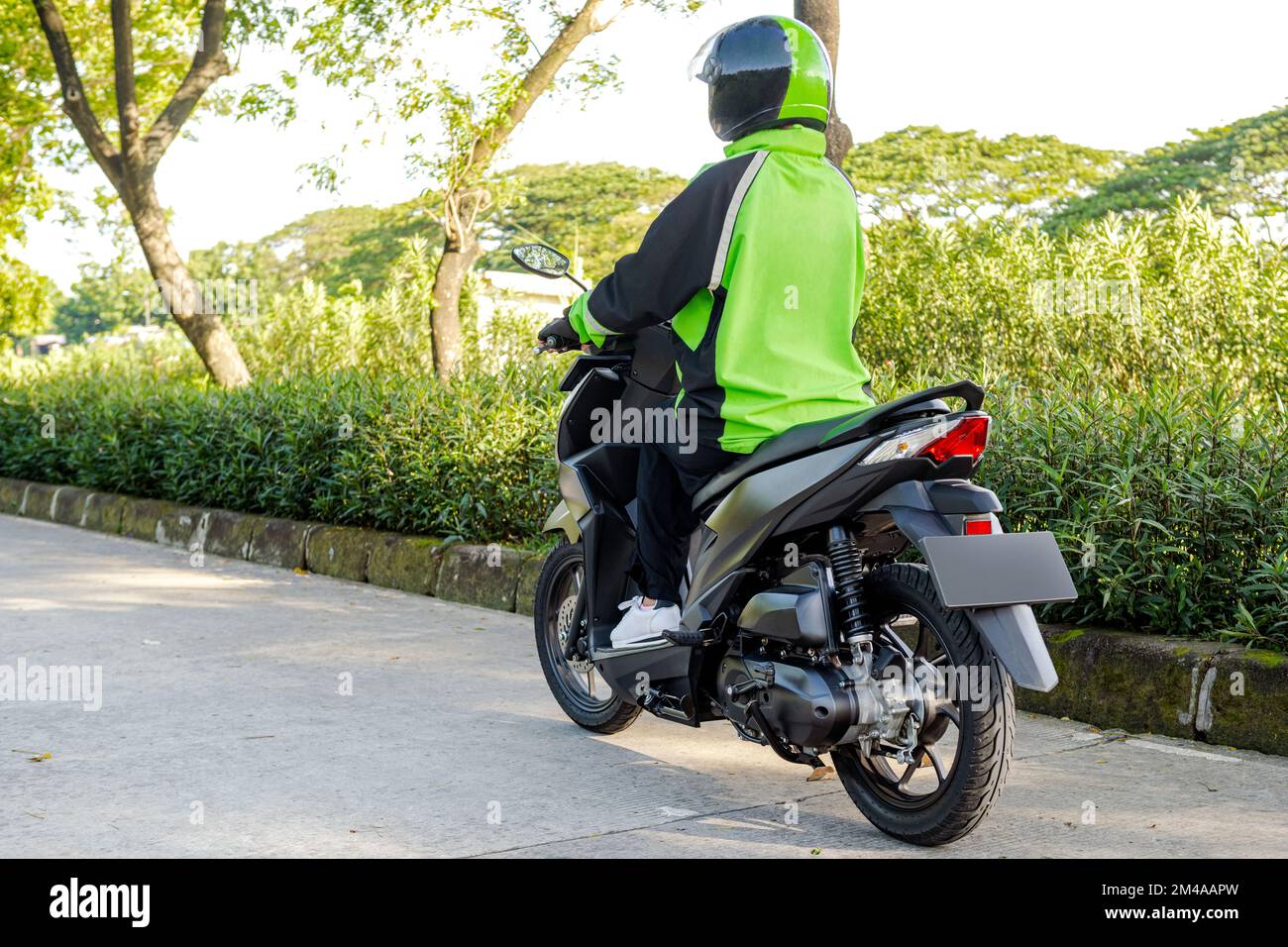 Rear view of an Asian woman working as a motorcycle taxi driver on the ...