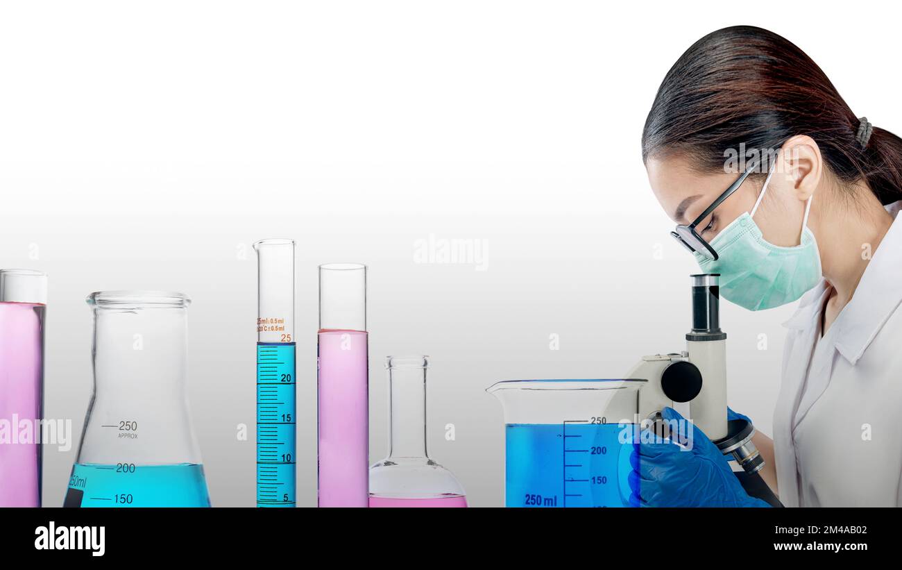 Asian female scientists using a microscope with colorful chemicals in ...