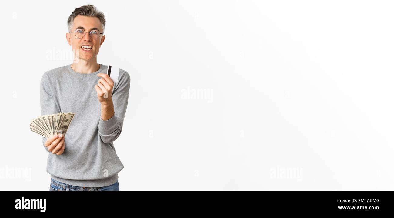 Portrait of excited middle-aged man looking amazed, holding money and ...