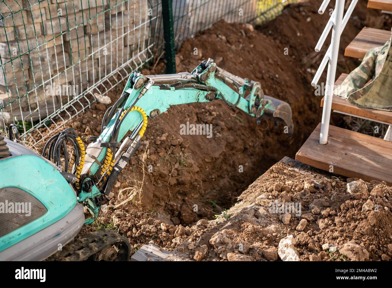 Mini excavator digs a trench to lay pipes. Close up of an excavator ...