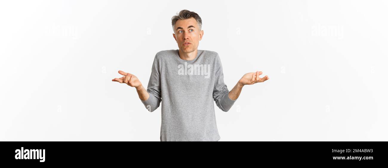 Image of confused middle-aged man with grey hair, shrugging and looking ...