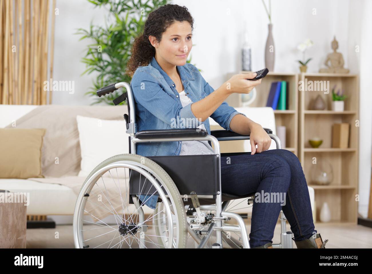woman in wheelchair using remote control Stock Photo - Alamy