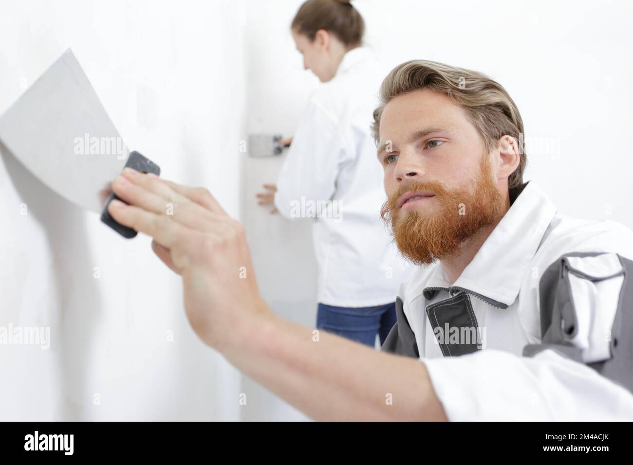 man spreading paint on wall Stock Photo - Alamy