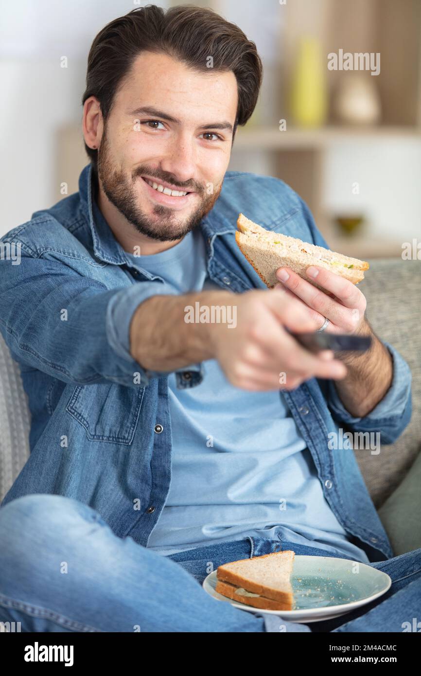 man changing tv channel with remote control while eating sandwich Stock ...