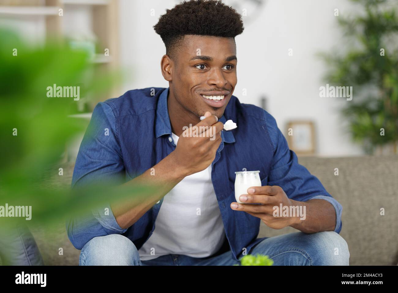 cheerful young man eating yogurt for breakfast Stock Photo - Alamy